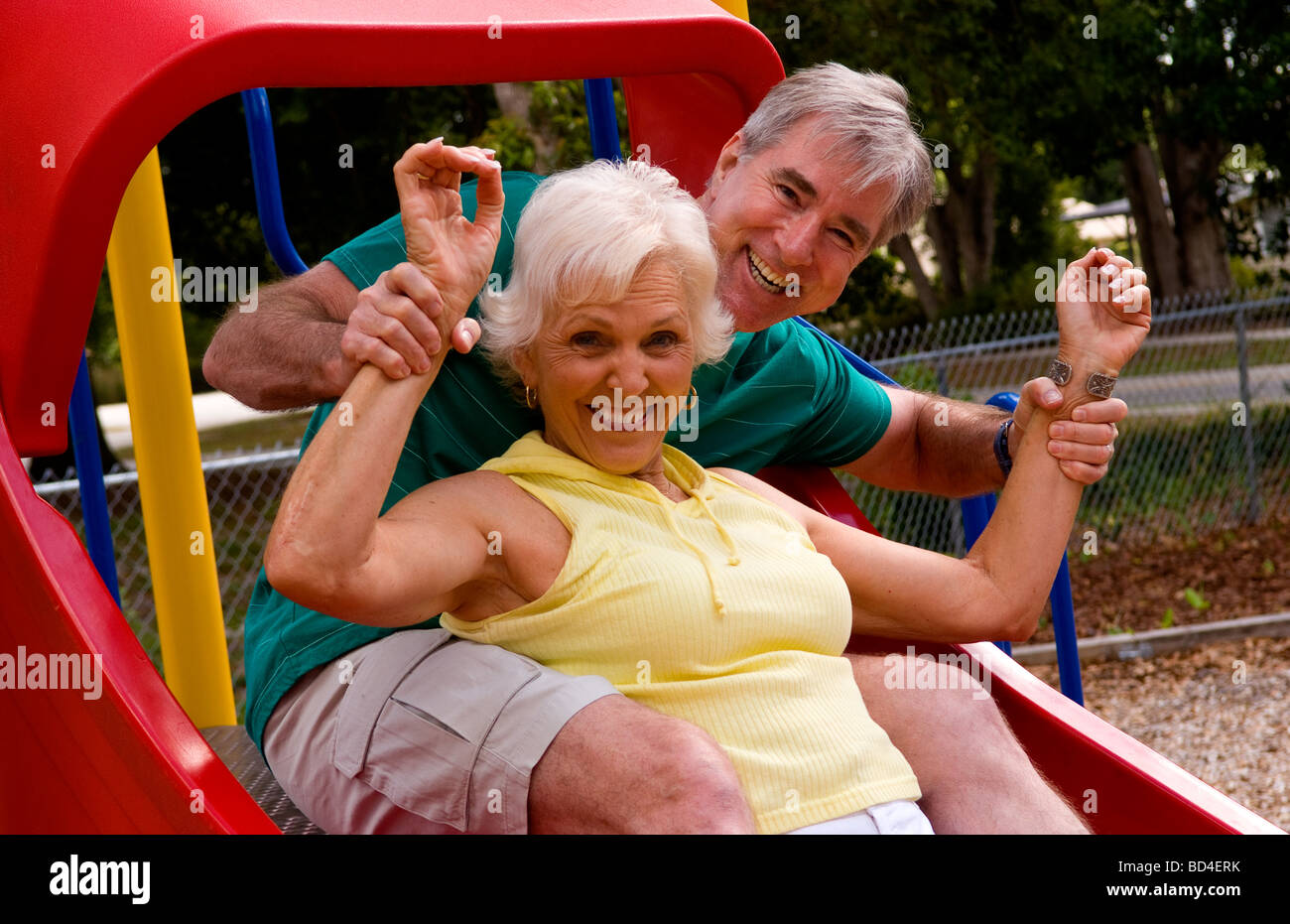 Senior retired couple having fun at playground outside with slide Stock ...