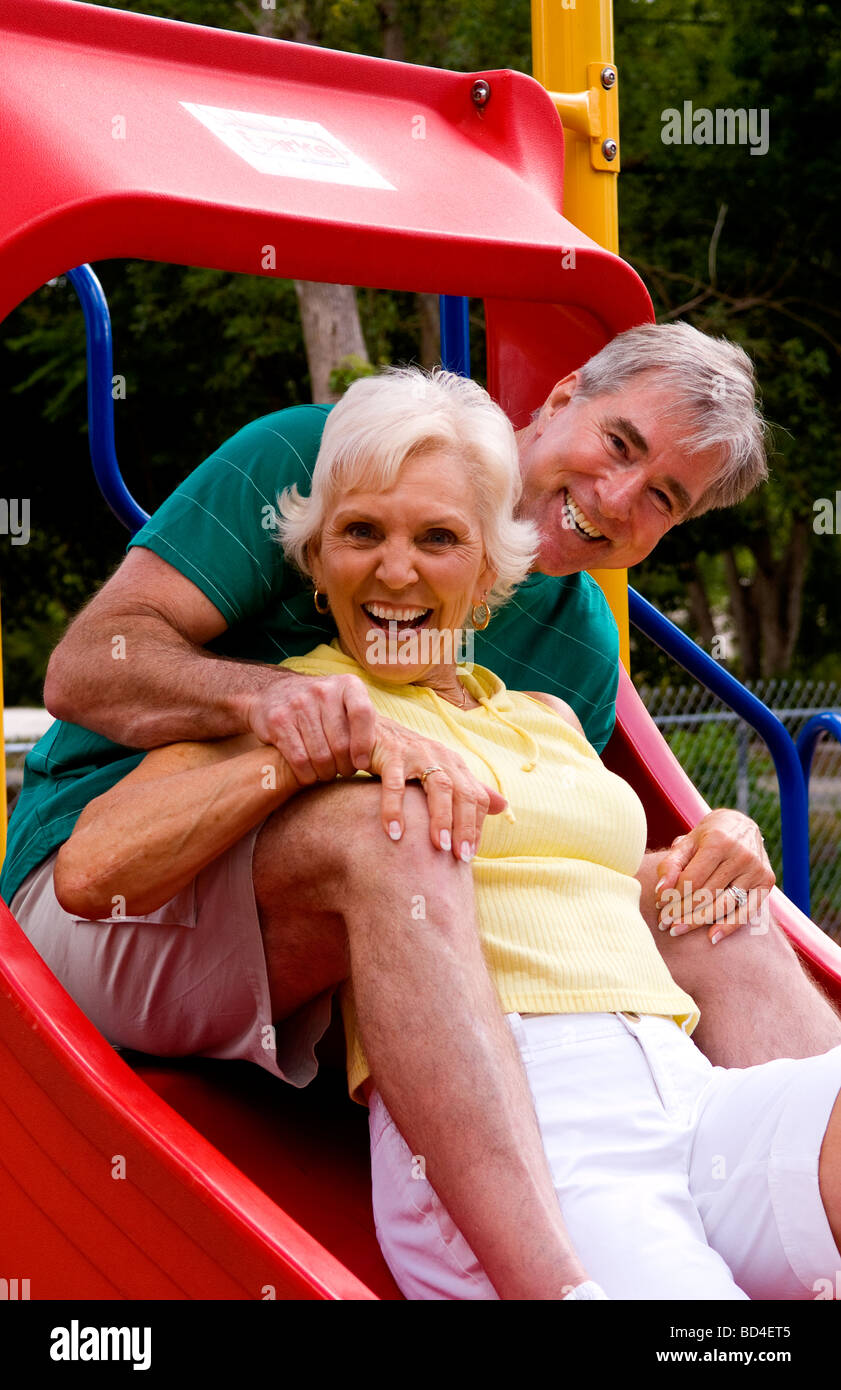 Senior retired couple having fun at playground outside with slide Stock ...