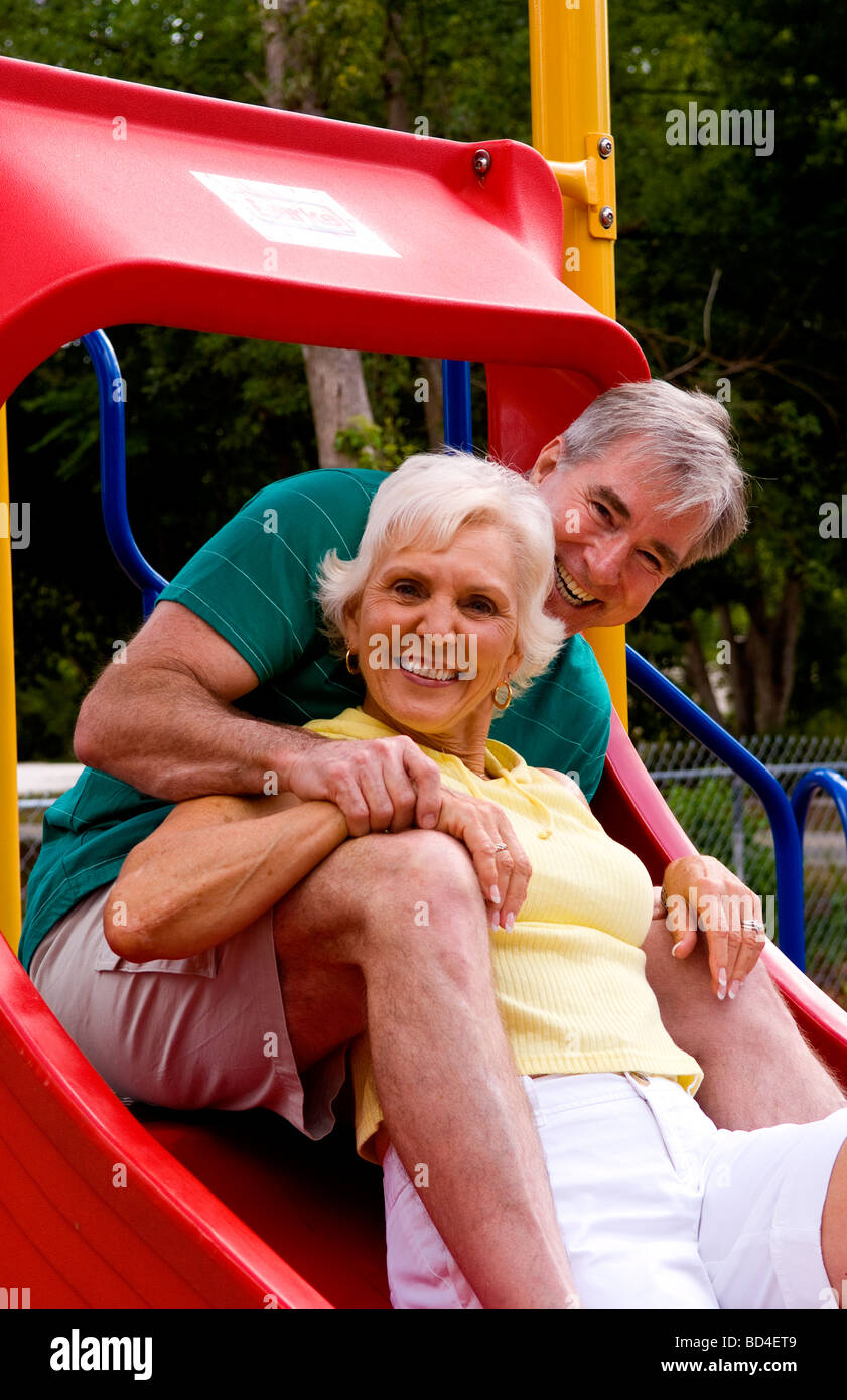 Senior retired couple having fun at playground outside with slide Stock ...