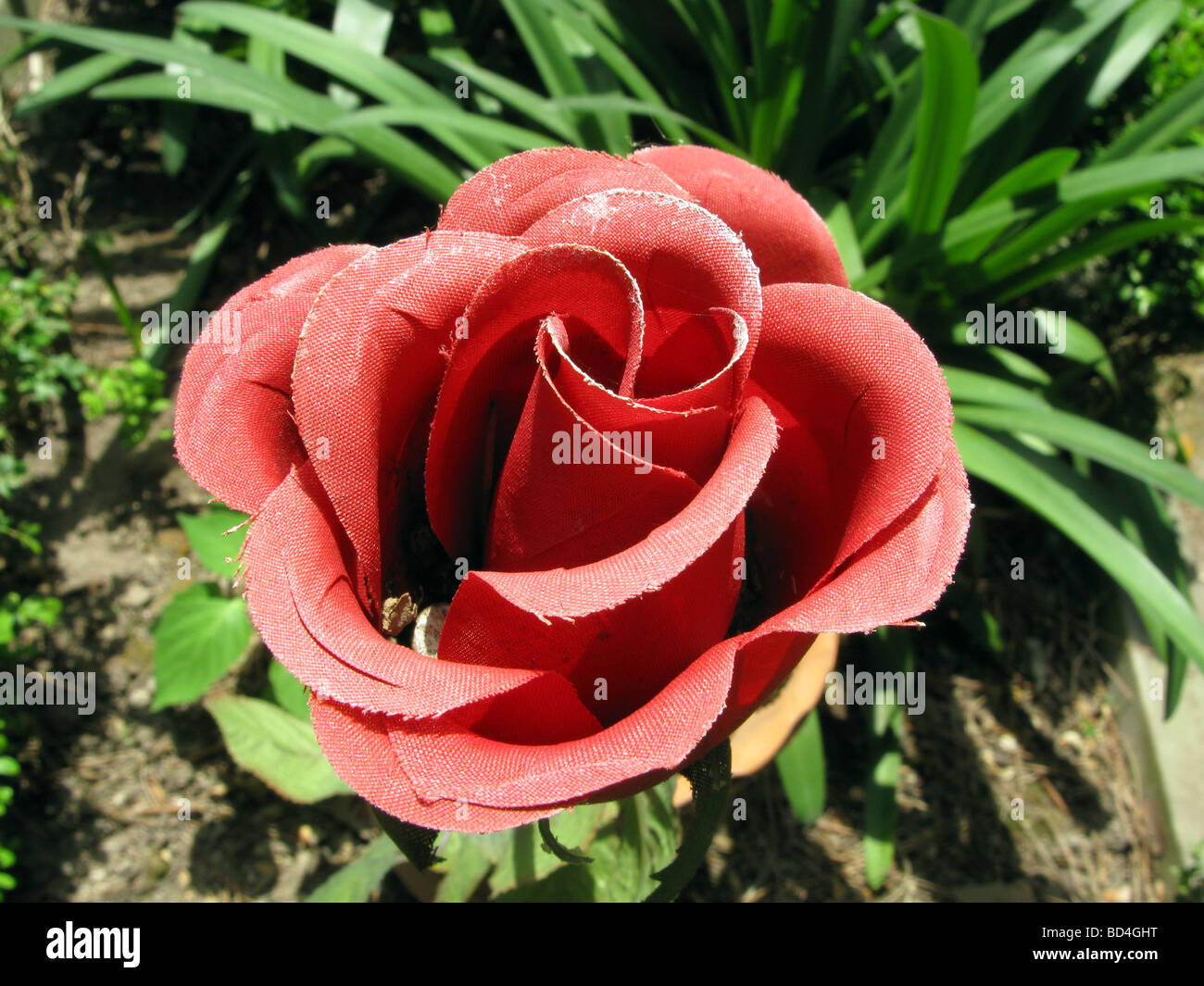 detail of red plastic artificial rose flower in garden Stock Photo - Alamy