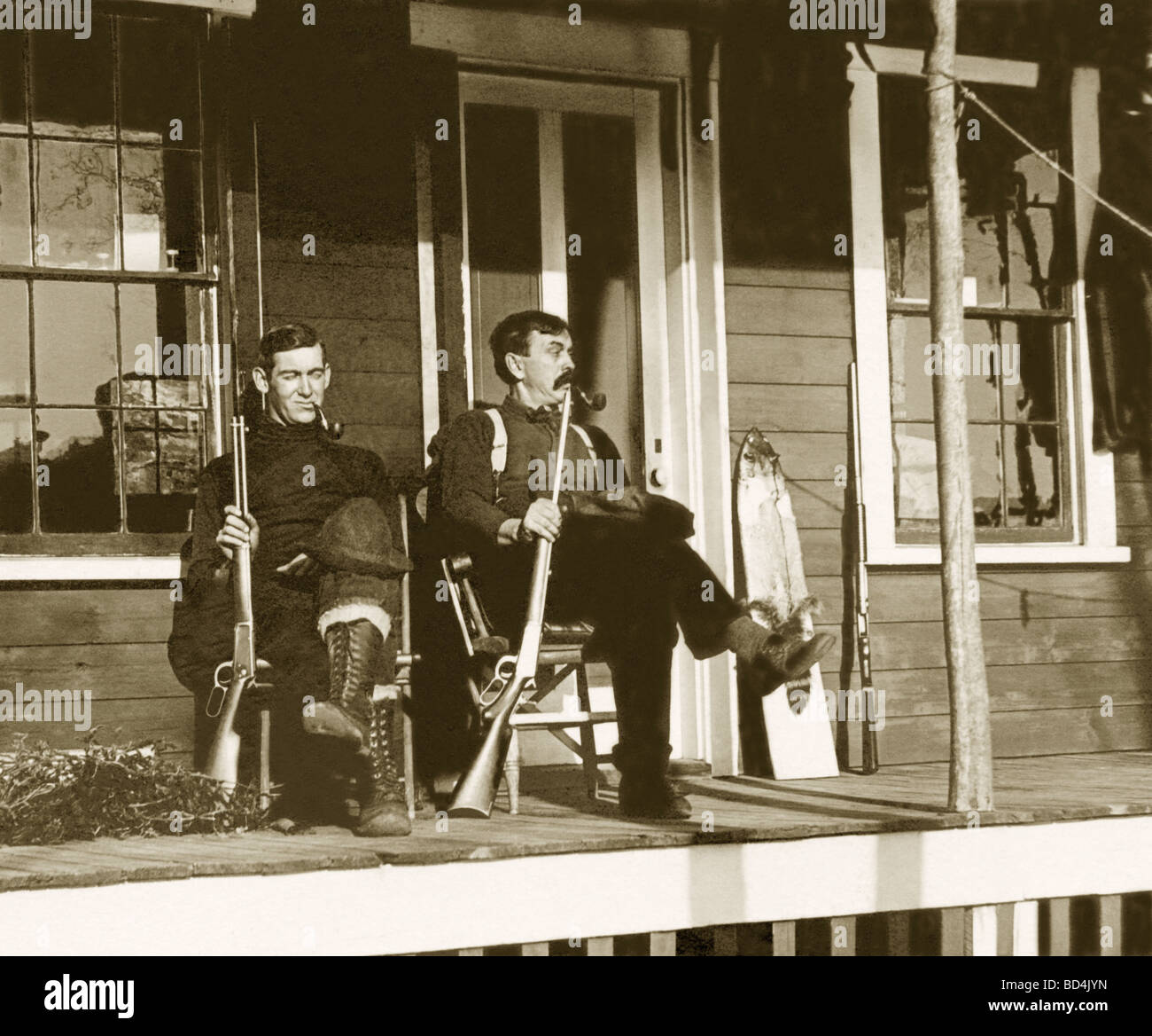 Two Hunters Relaxing on Porch of Hunting Cabin Stock Photo - Alamy