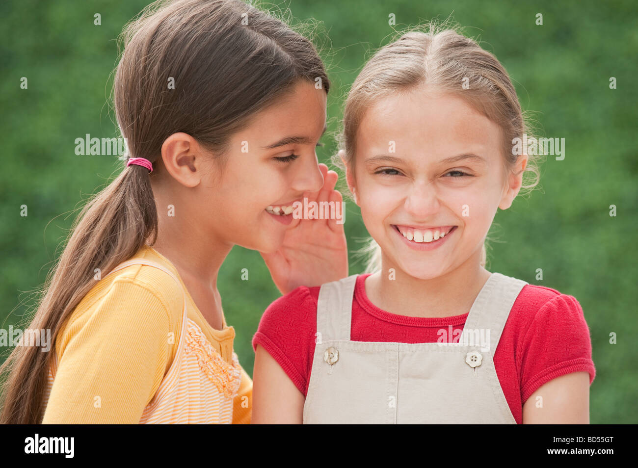 Two girl friends whispering Stock Photo - Alamy