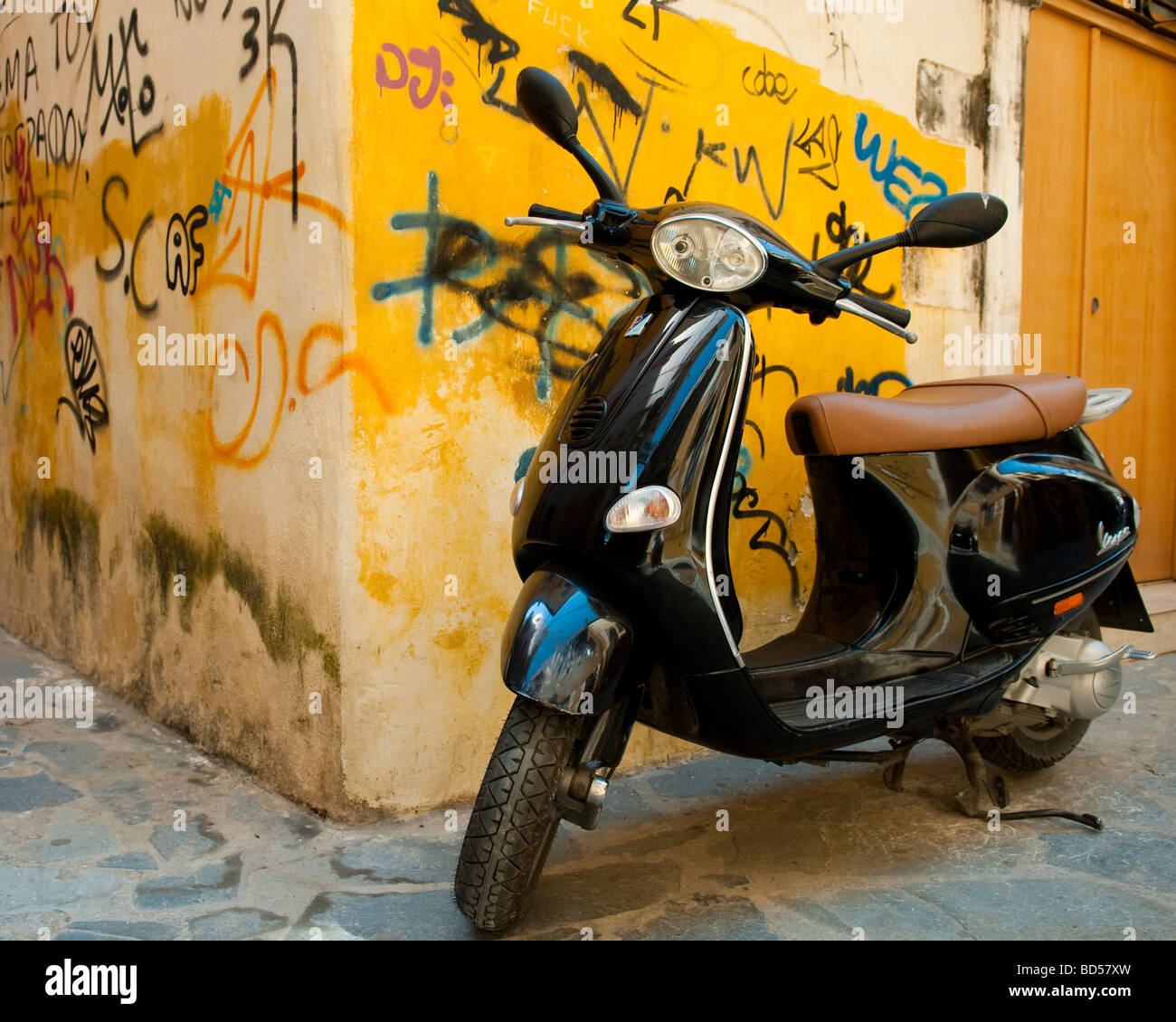 Black scooter and yellow wall with graffiti. Chania, Crete, Greece ...