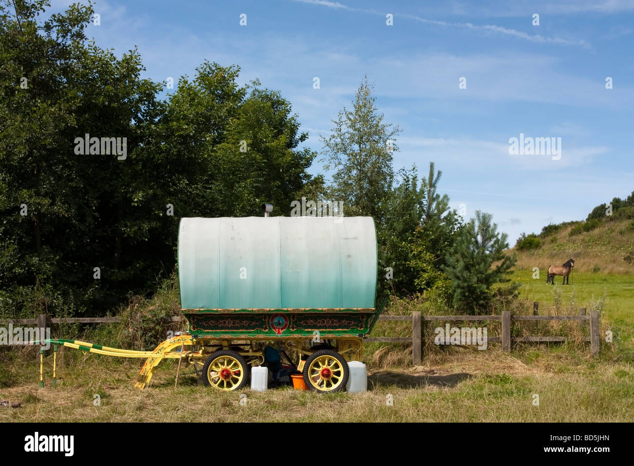view of horse drawn Romany Gypsy caravan camp by the side of quiet b ...