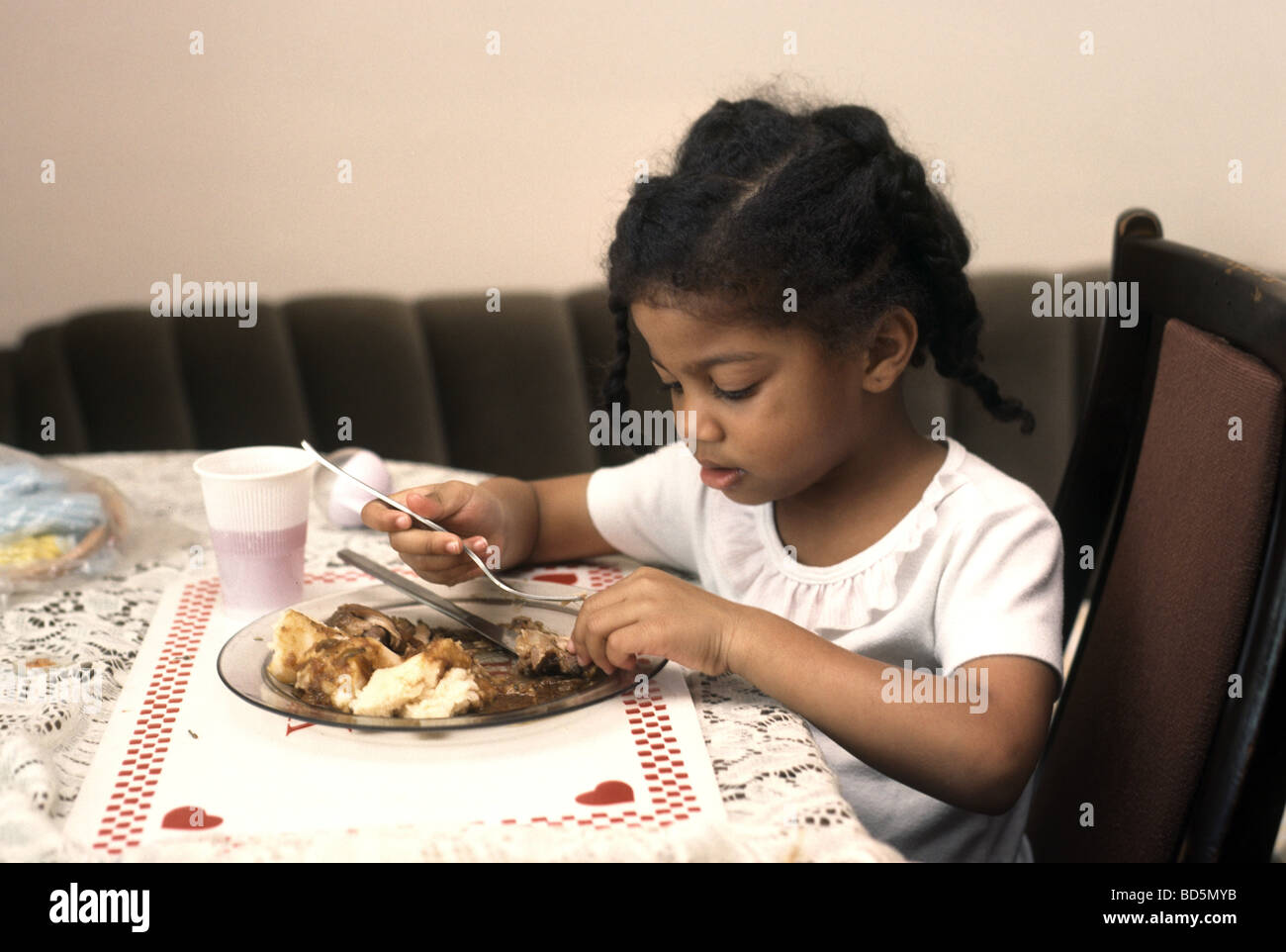 young Black girl eating Sunday dinner of chicken gravy and mash ...