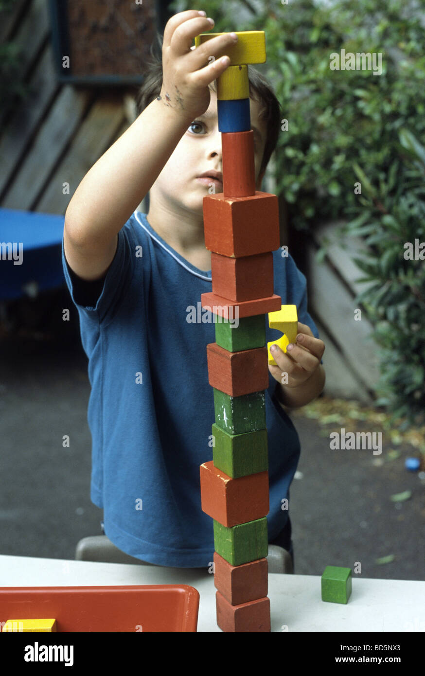young boy in primary school playground playing with building blocks ...