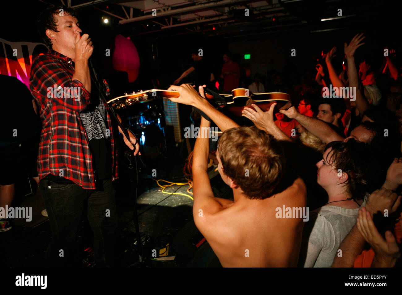 Randy Randall, of No Age, sings while the crowd plays his guitar in ...