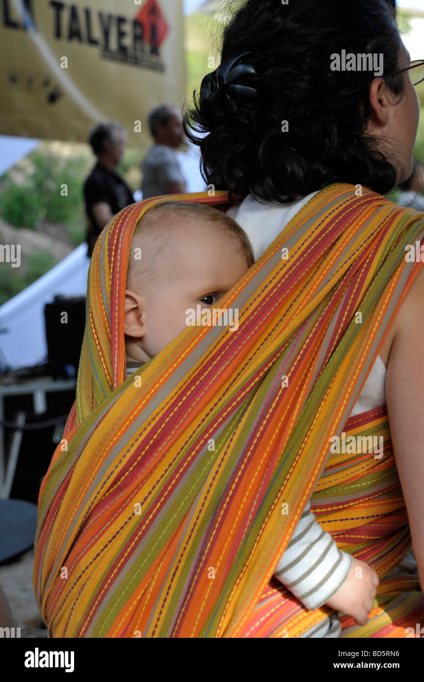 Mother carrying young baby on her back in a colorful sling Stock Photo ...