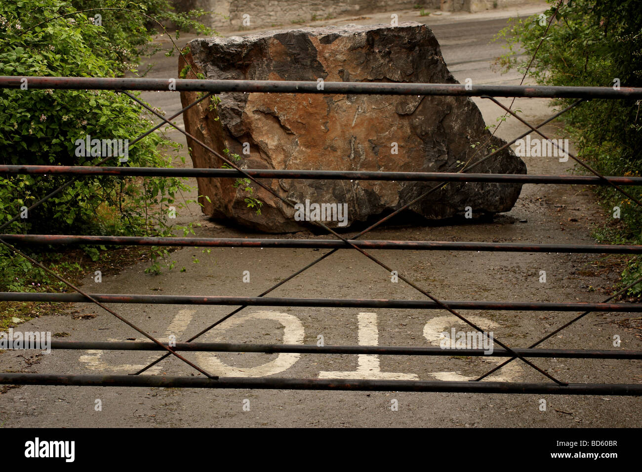 Large rock blocking a closed gateway with stop sign Stock Photo - Alamy
