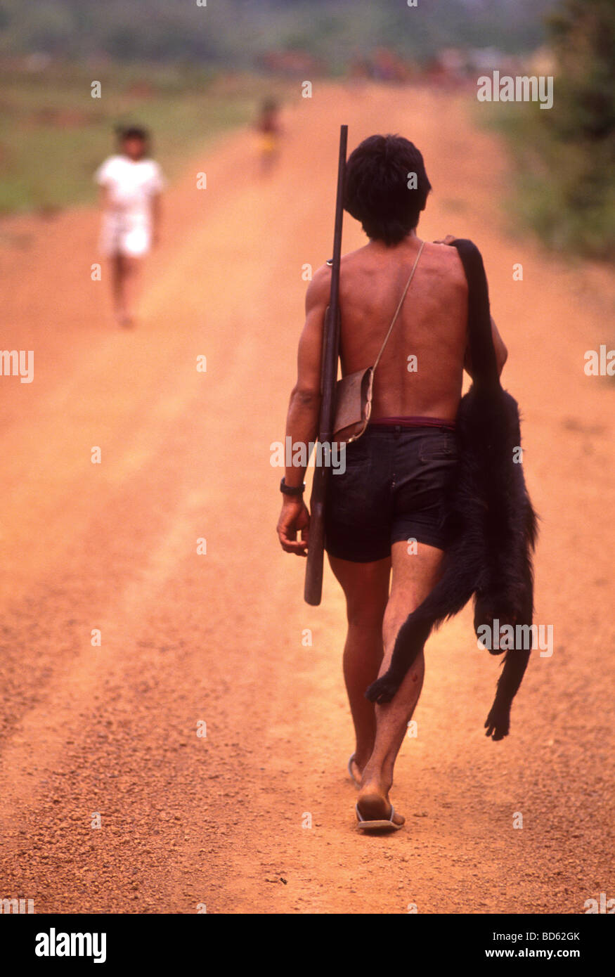 Hunter with shot gun carries monkey Transamazônica road Amazon rain ...