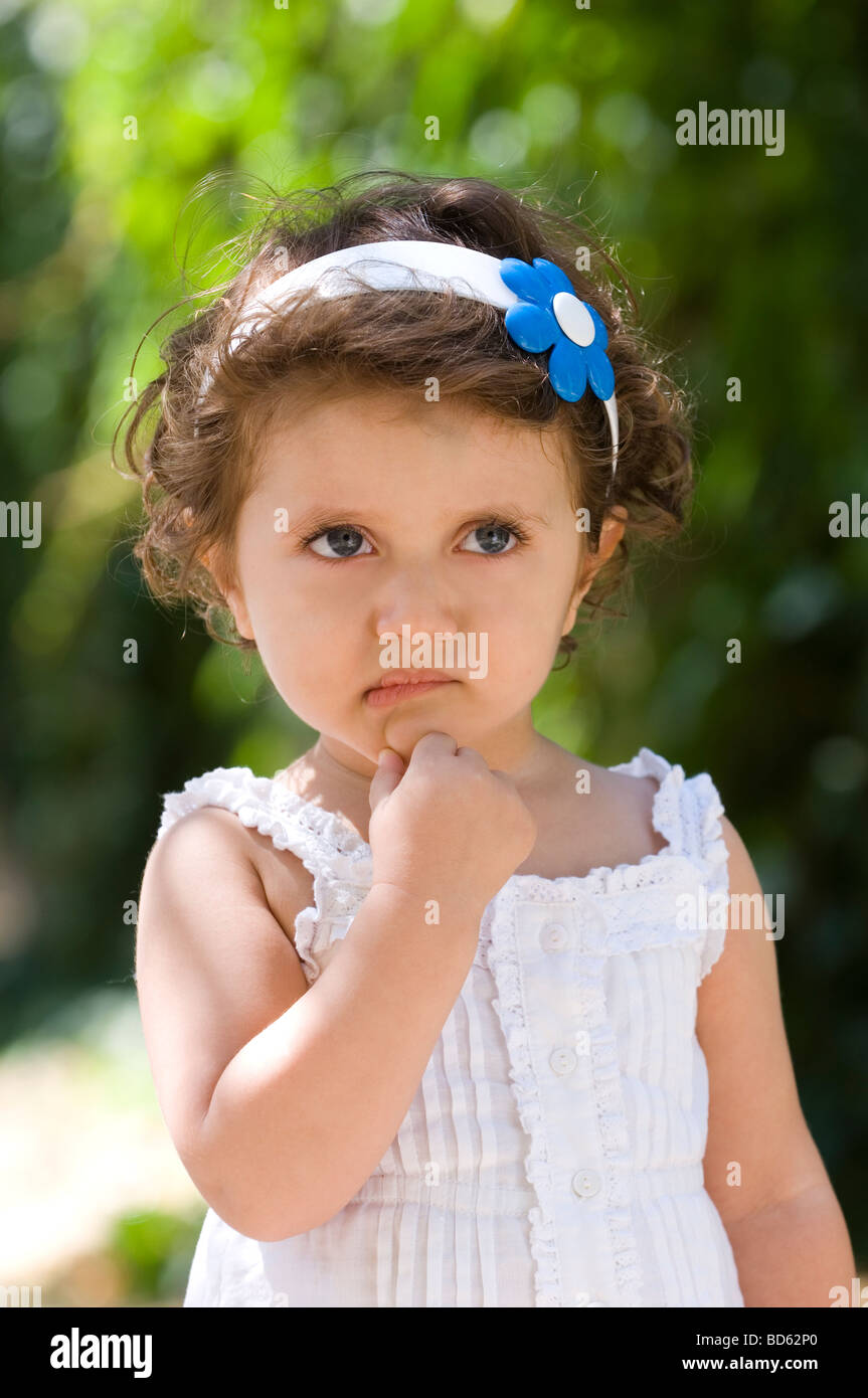 Little girl with hand over chin outdoors Stock Photo - Alamy