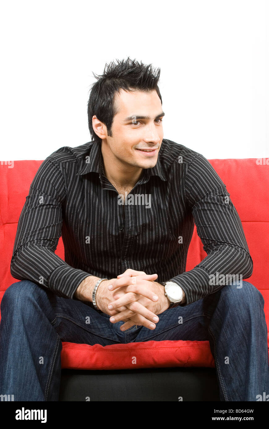 Happy man sitting on red sofa Stock Photo - Alamy