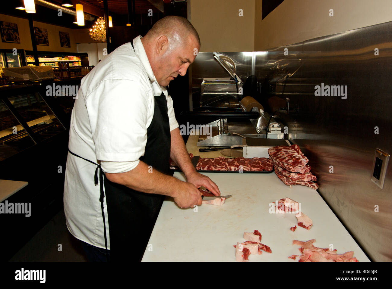 Butcher cutting trimming fat from strip loin beef steaks Stock Photo ...