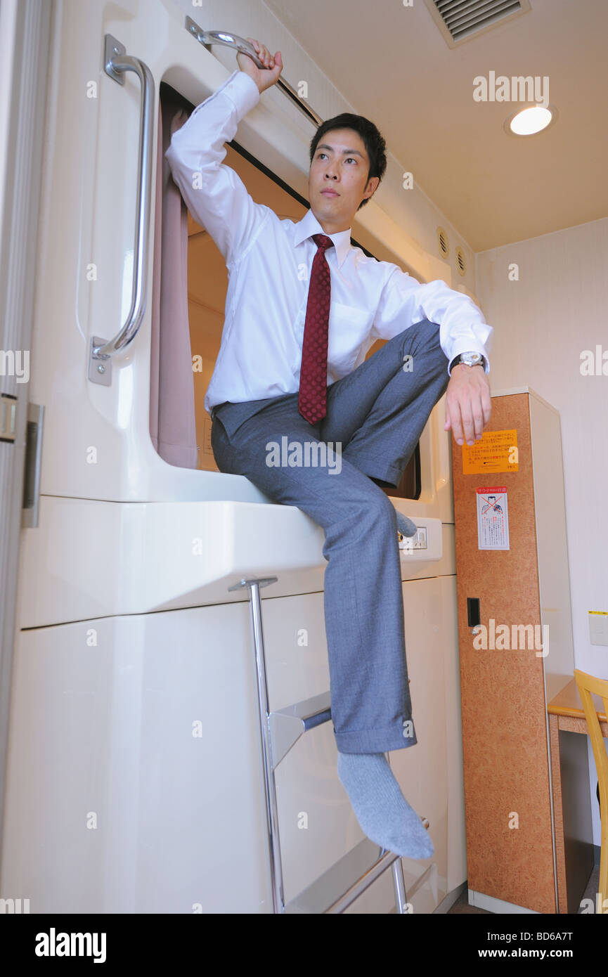 Man sitting in capsule hotel Stock Photo - Alamy