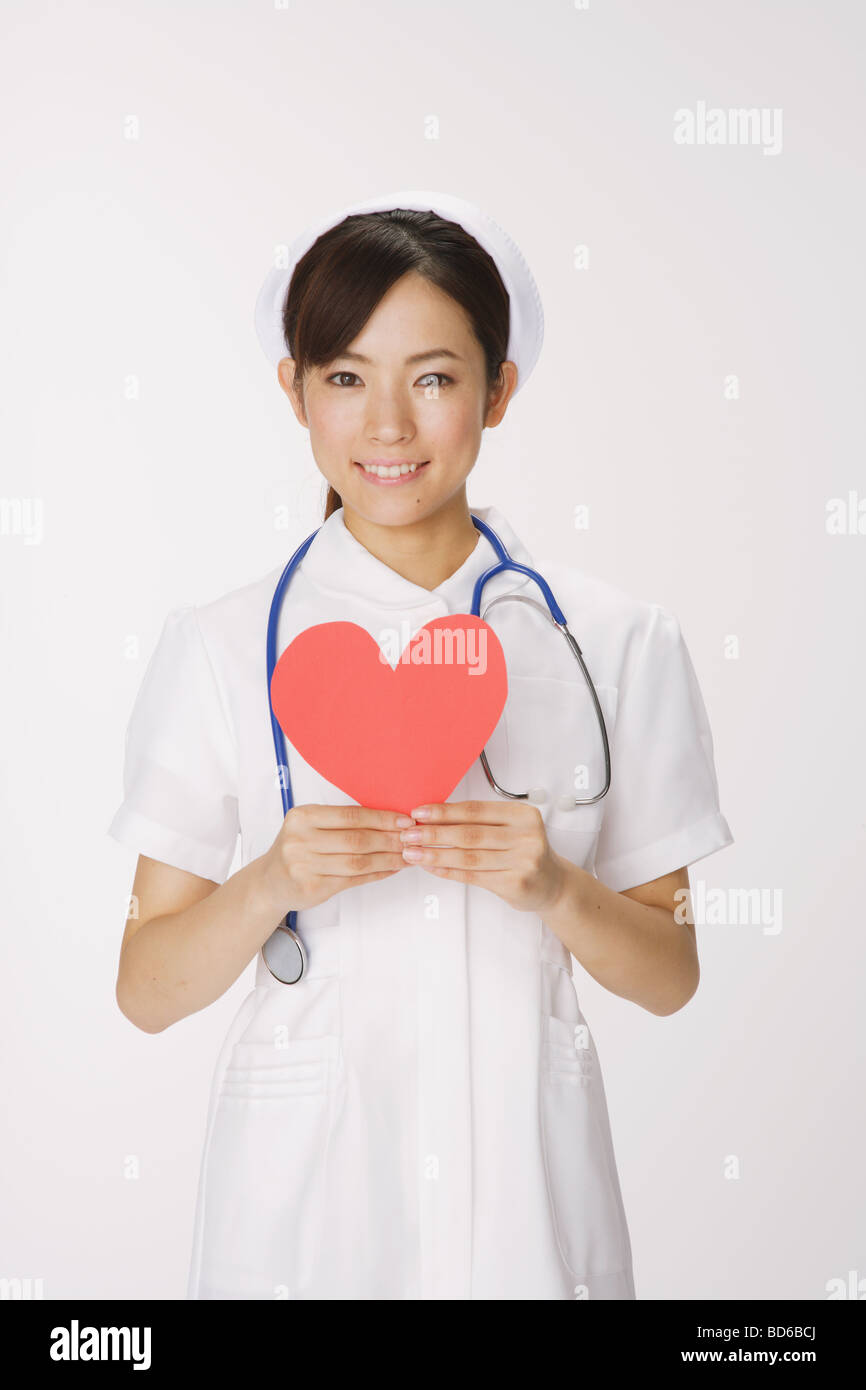 Smiling nurse standing holding heart Stock Photo - Alamy