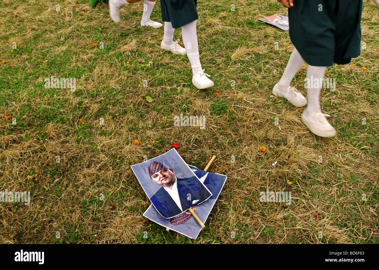 Children march past discarded posters of King Gyanendra and Queen Komal ...