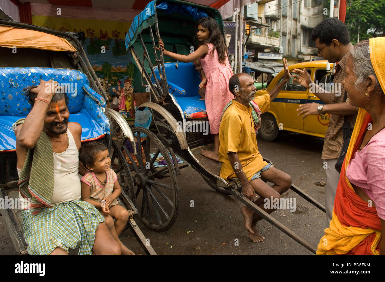 Rickshaw drivers talk with their friends and families on a busy street ...