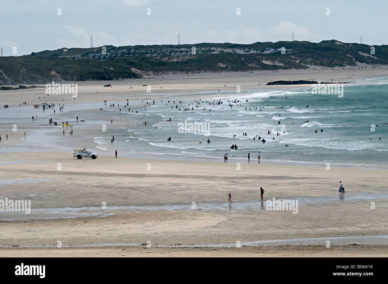 view of gwithian beach in cornwall with many people in the water ...