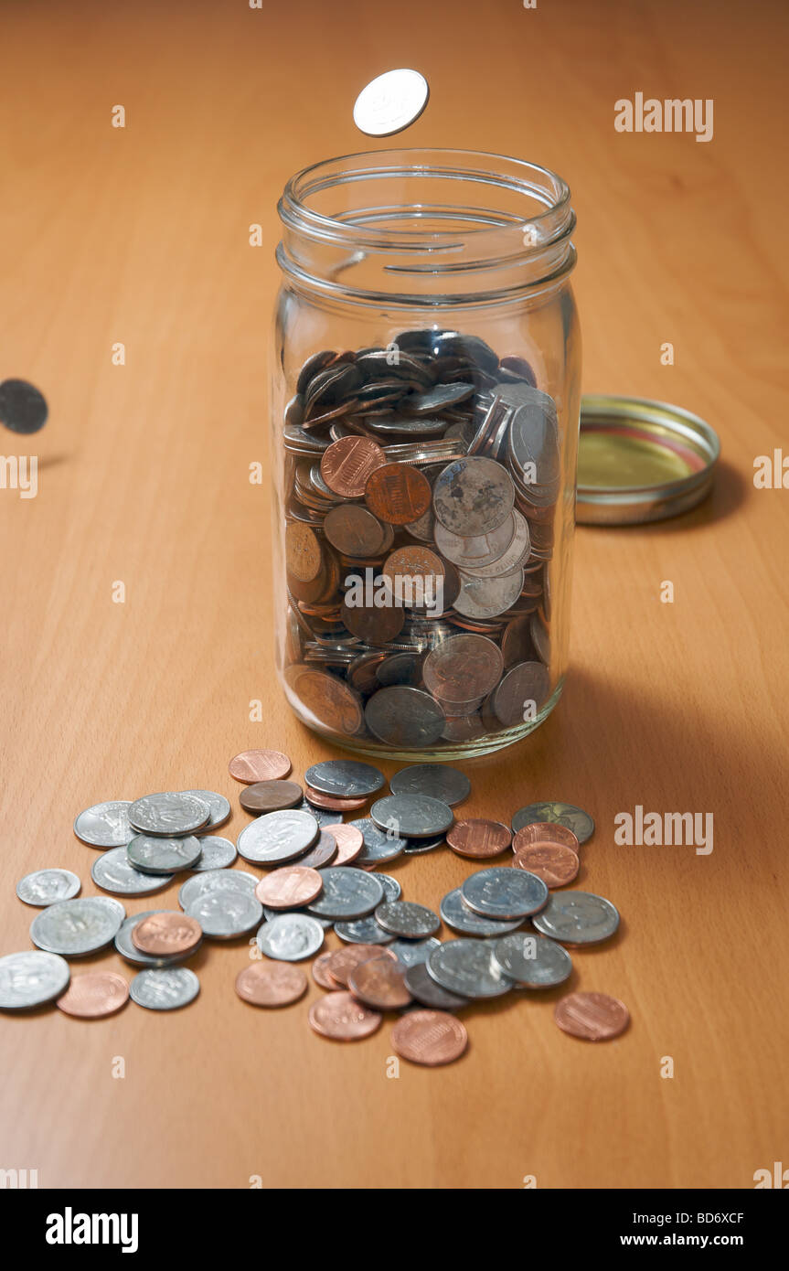 Dropping coins into a jar Stock Photo - Alamy