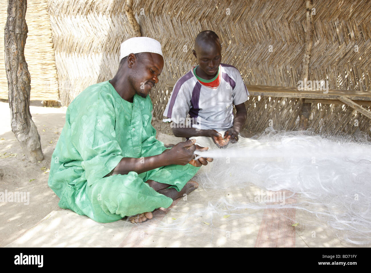 Fishermen knotting a fishing net on Lagdo Lake, northern Cameroon ...