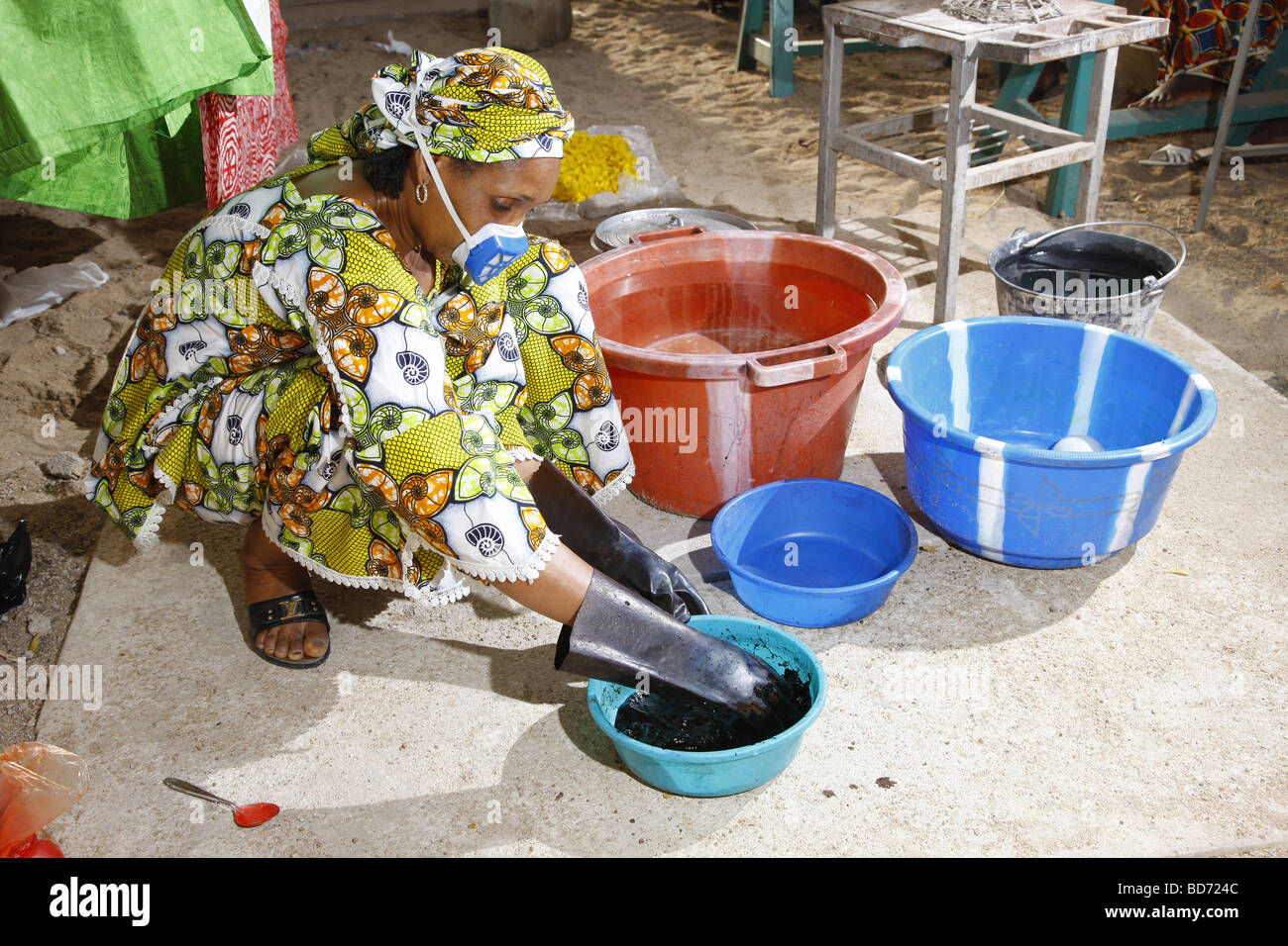Woman wearing a respirator while mixing colours for batik dyeing ...