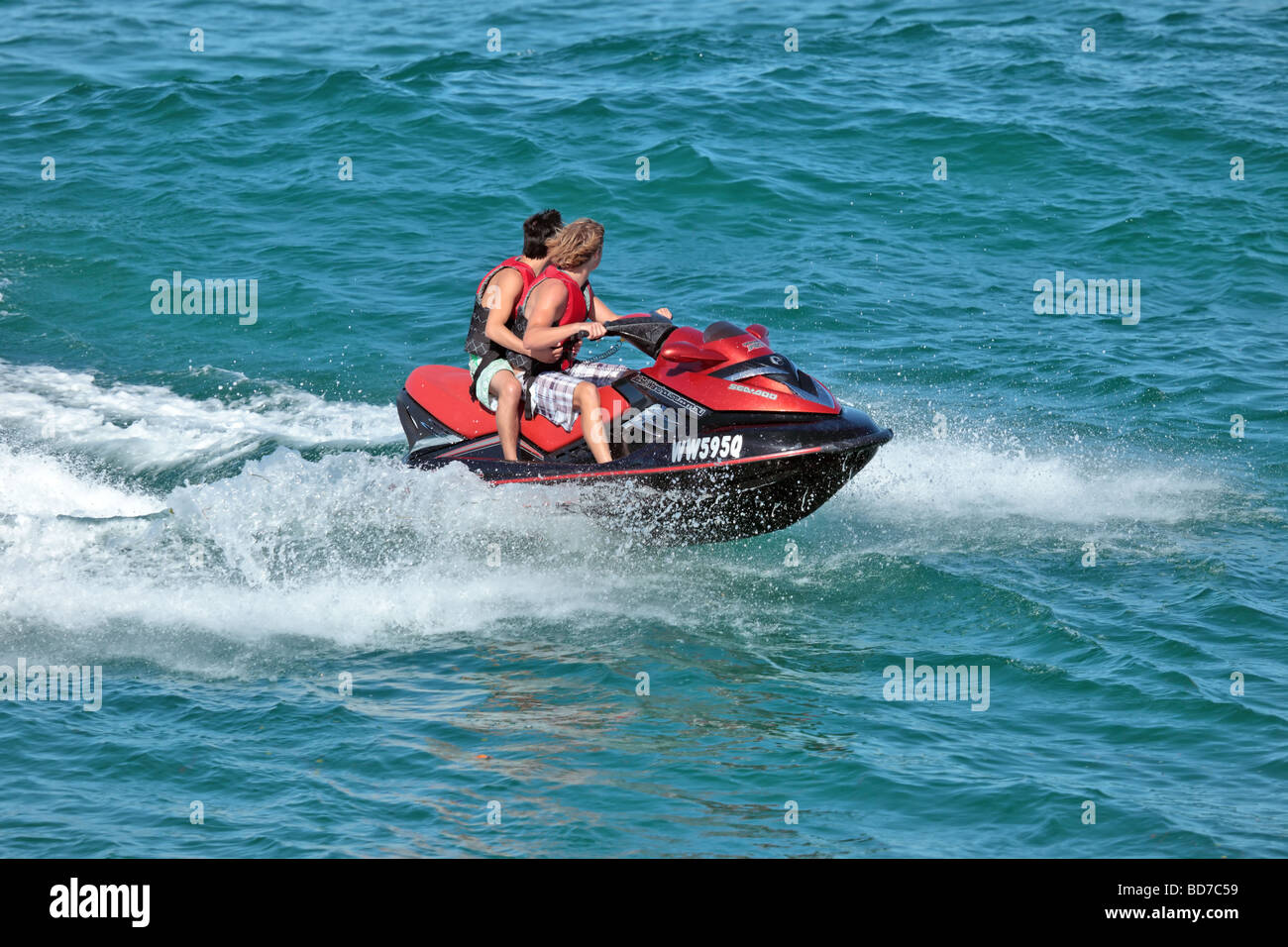 Men riding on a jetski producing large wake Stock Photo - Alamy