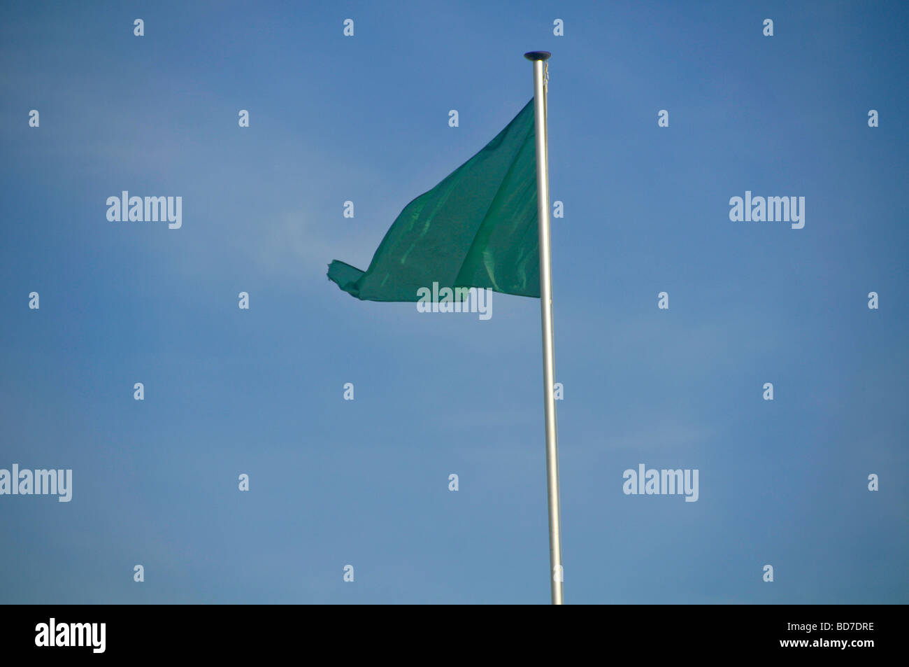 Green flag flying in the wind in blue sky Stock Photo - Alamy