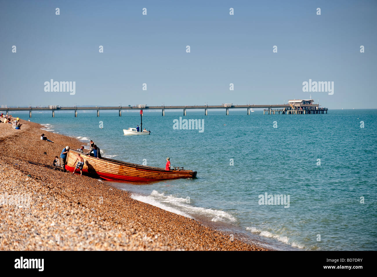 Fishing boat being pulled ashore at Walmer Beach, Kent, with Deal Pier ...