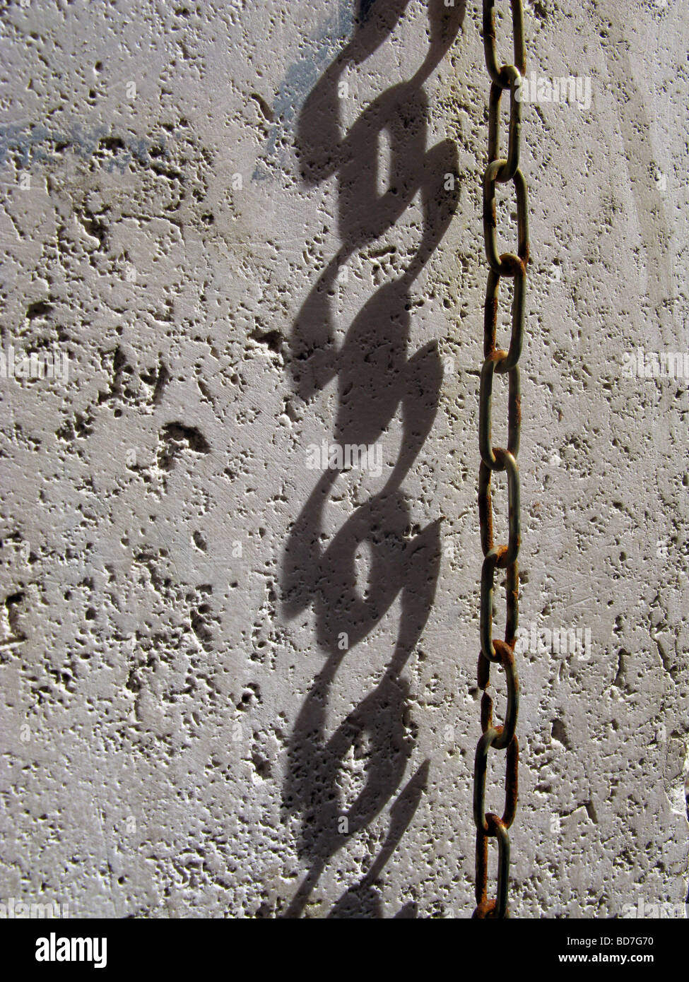 old rusty hanging chain by wall in sun Stock Photo - Alamy