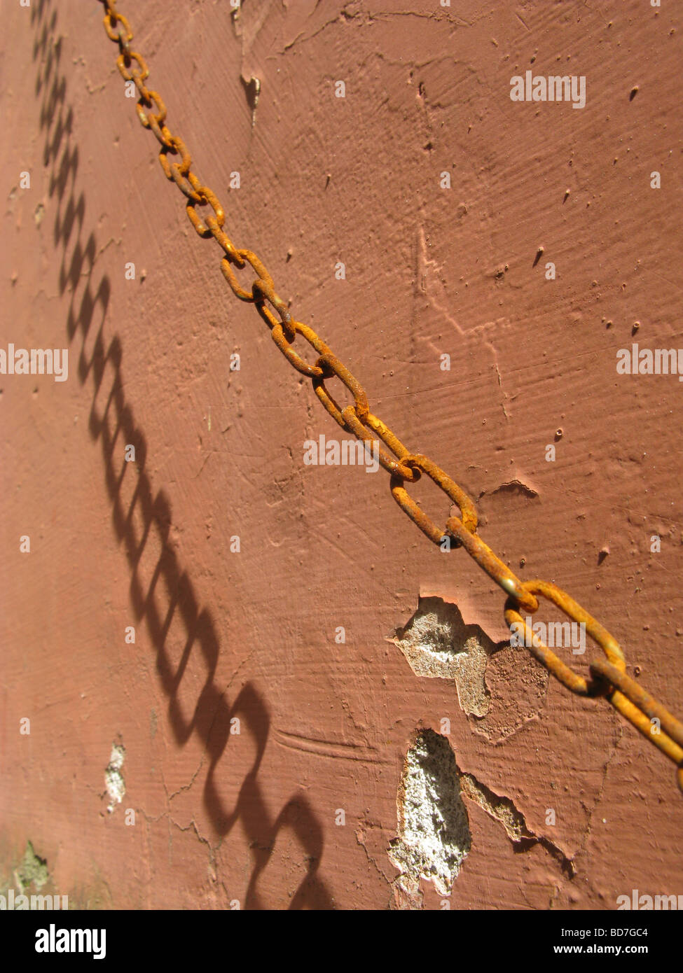 old rusty hanging chain by wall in sun Stock Photo - Alamy