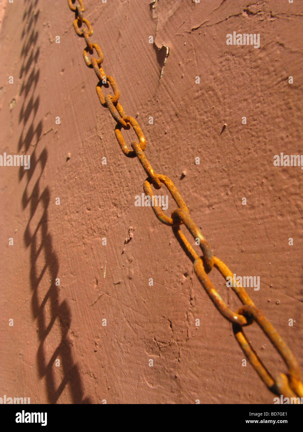 old rusty hanging chain by wall in sun Stock Photo - Alamy