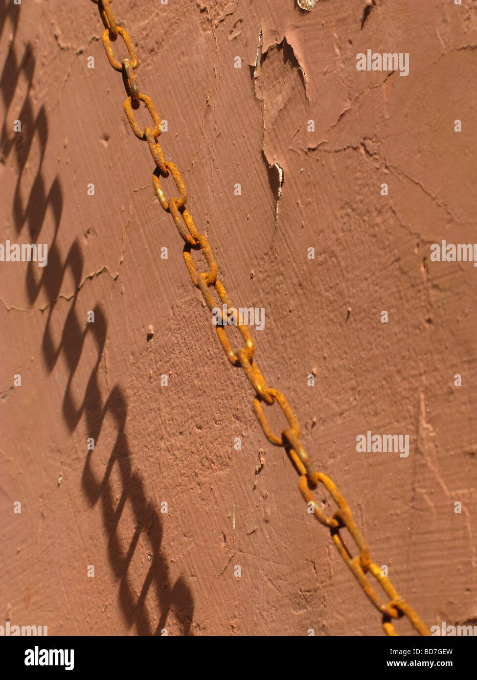old rusty hanging chain by wall in sun Stock Photo - Alamy