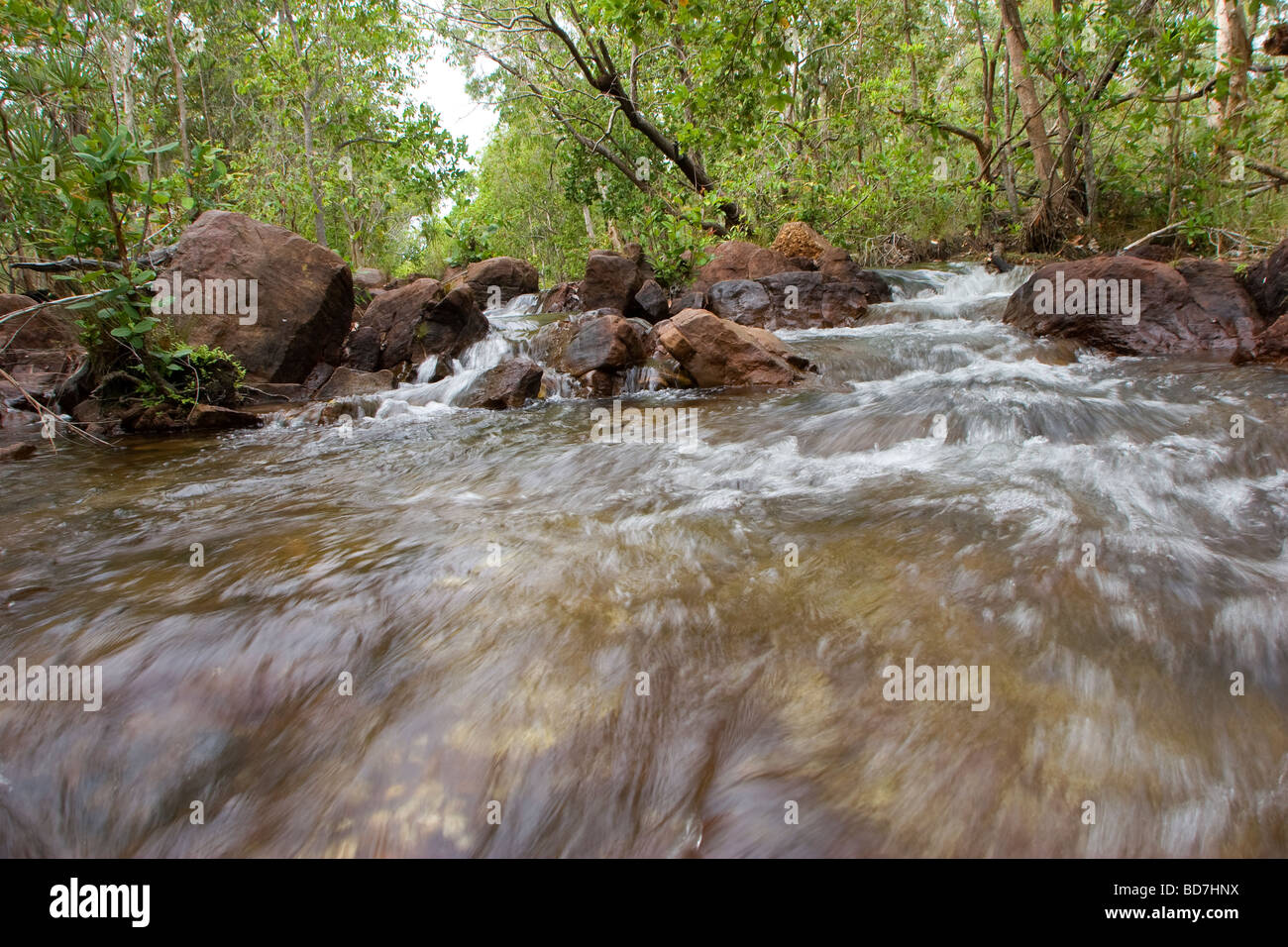A natural stream of clear, fresh water flows over rocks in the ...