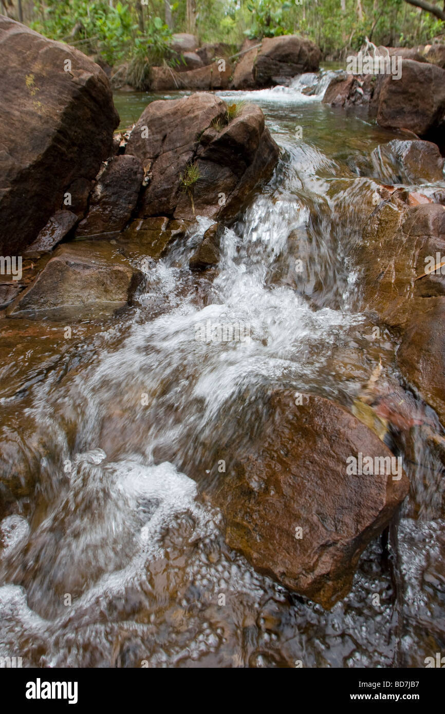 A natural stream of clear, fresh water flows over rocks in the ...