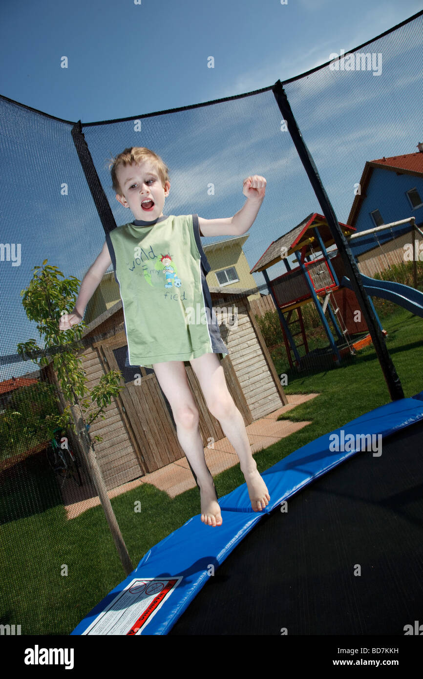 little boy jumping on trampoline in garden Stock Photo - Alamy
