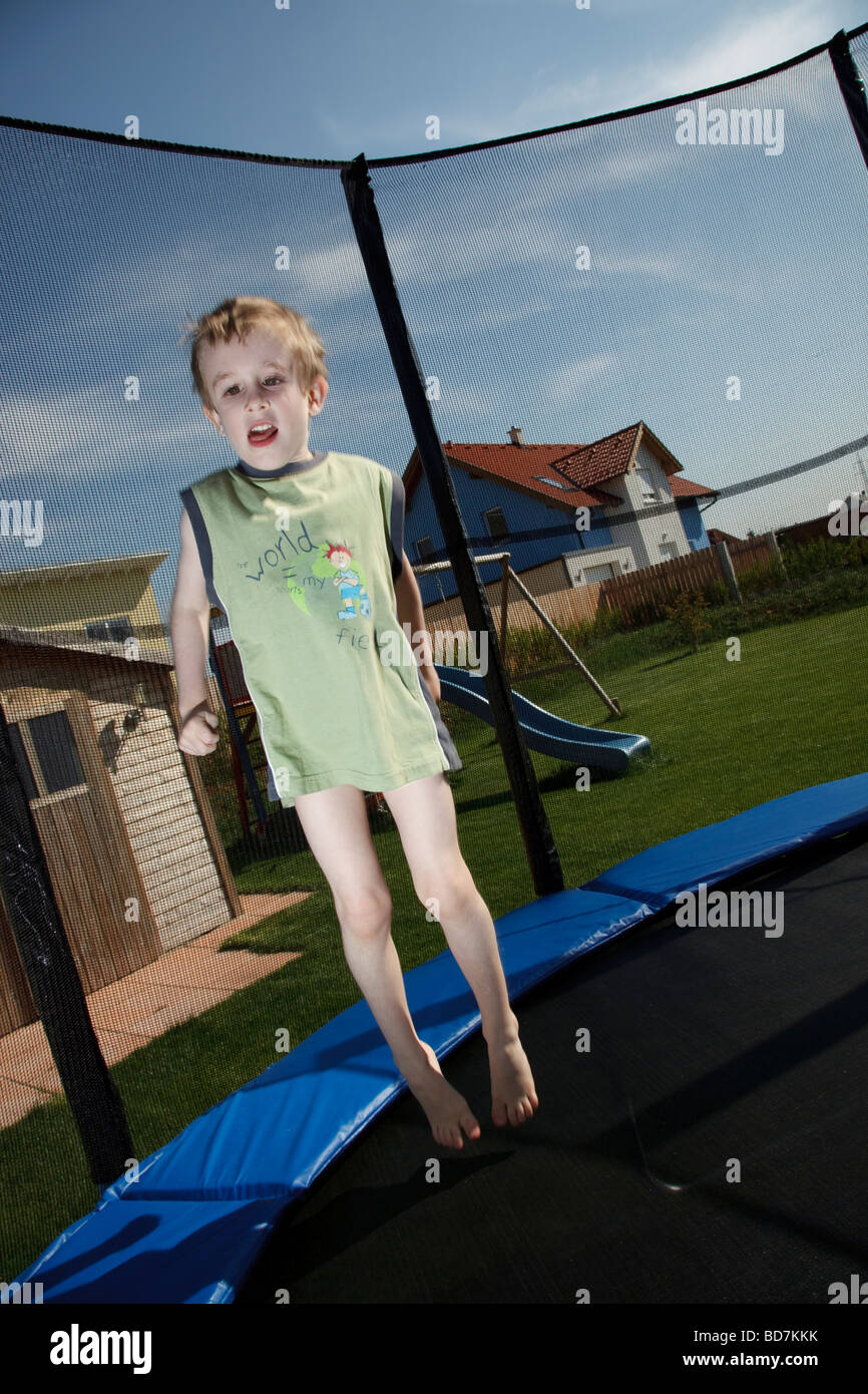 little boy jumping on trampoline in garden Stock Photo - Alamy