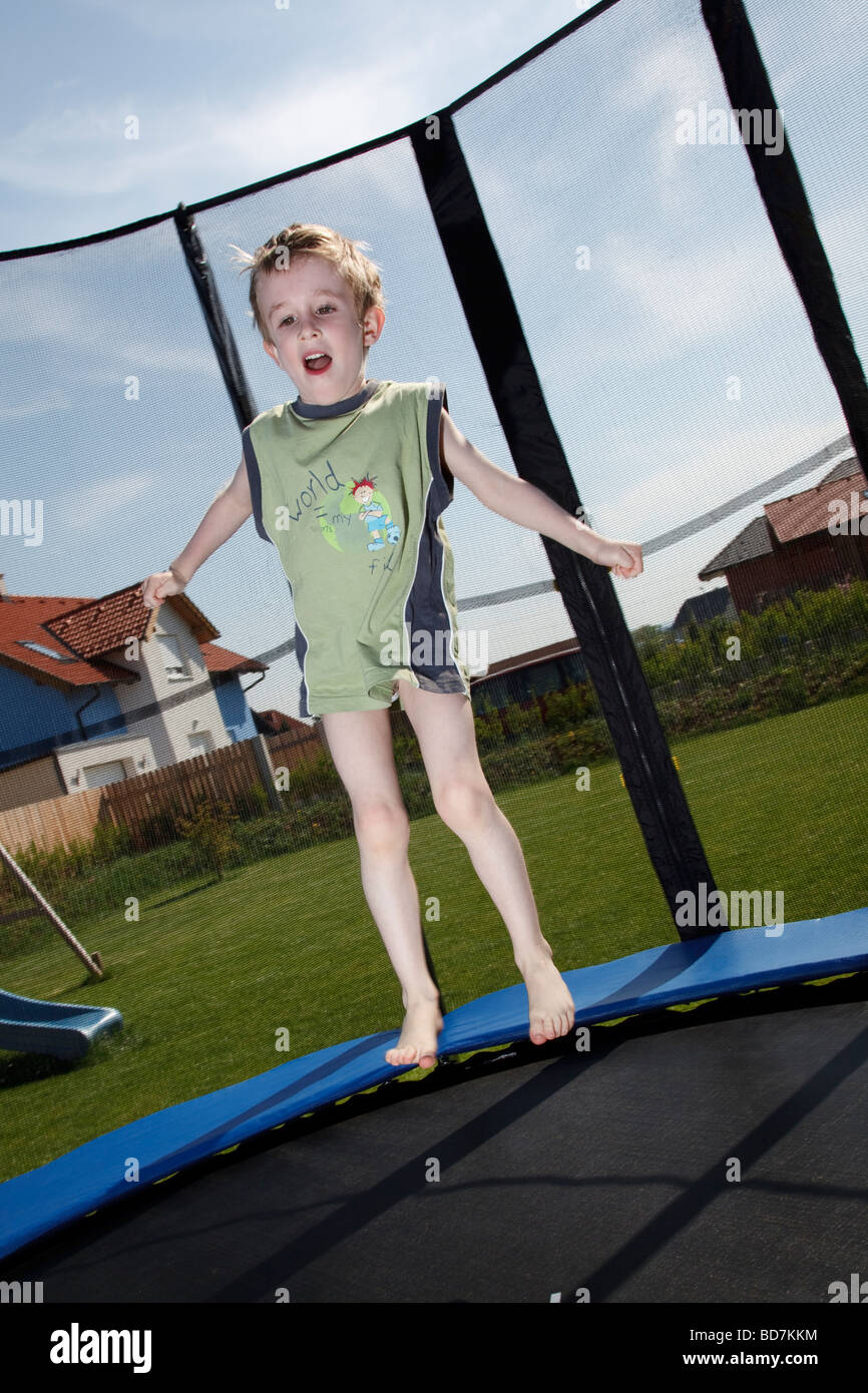 little boy jumping on trampoline in garden Stock Photo - Alamy