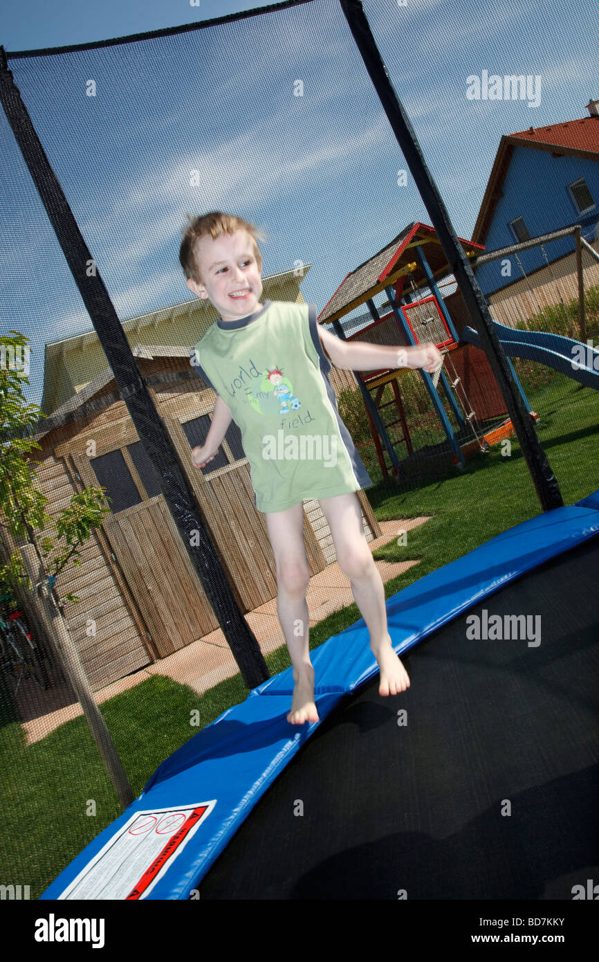 little boy jumping on trampoline in garden Stock Photo - Alamy