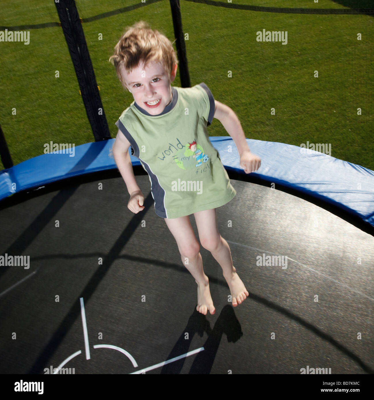 little boy jumping on trampoline in garden Stock Photo - Alamy