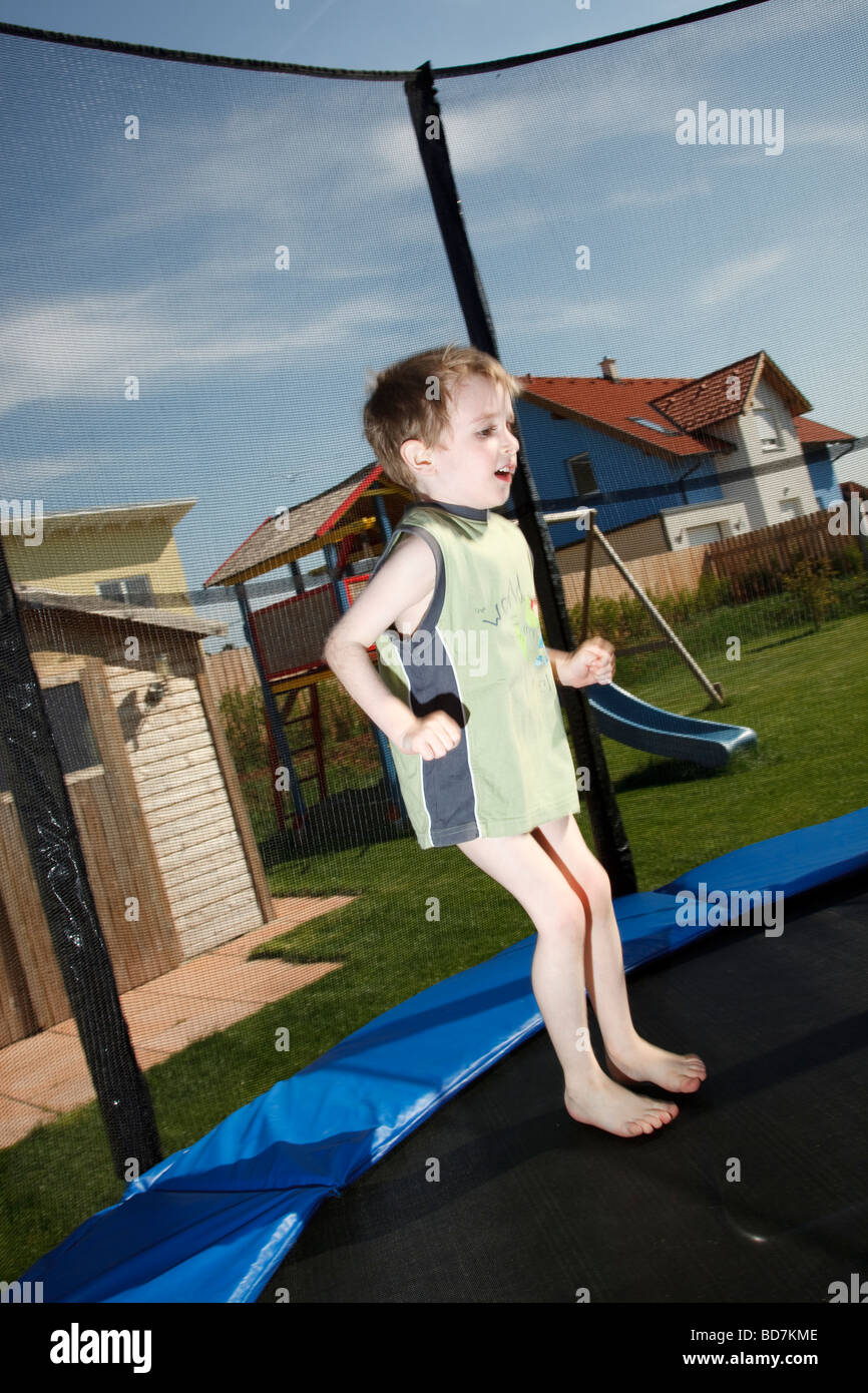 little boy jumping on trampoline in garden Stock Photo - Alamy