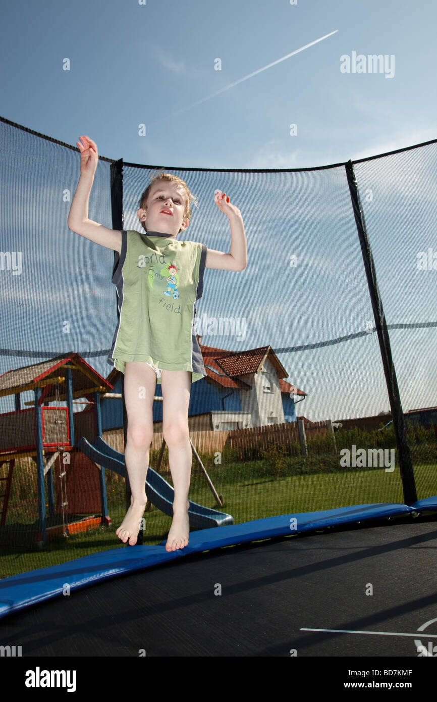 little boy jumping on trampoline in garden Stock Photo - Alamy