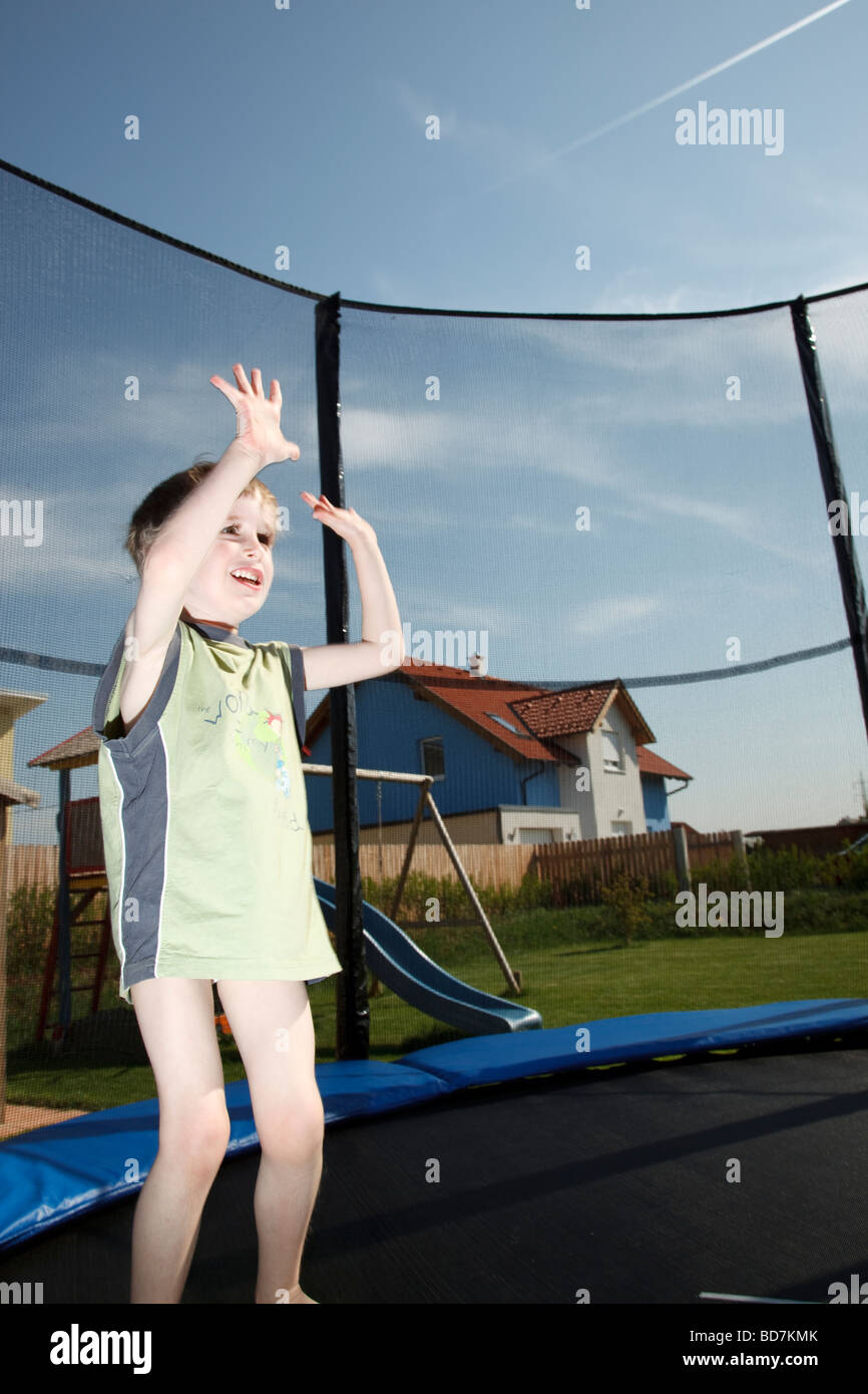 little boy jumping on trampoline in garden Stock Photo - Alamy
