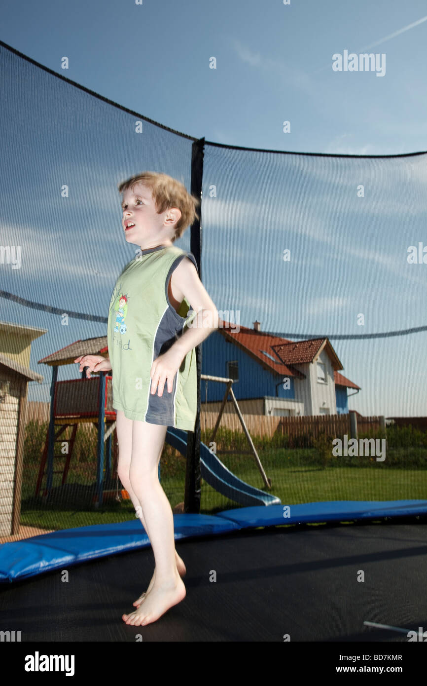 little boy jumping on trampoline in garden Stock Photo - Alamy