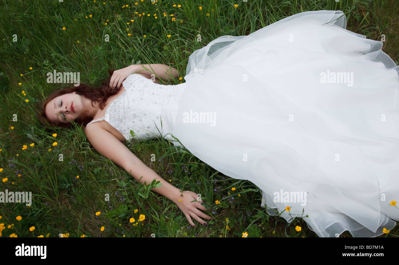 young woman in bridal dress lying in grass Stock Photo - Alamy