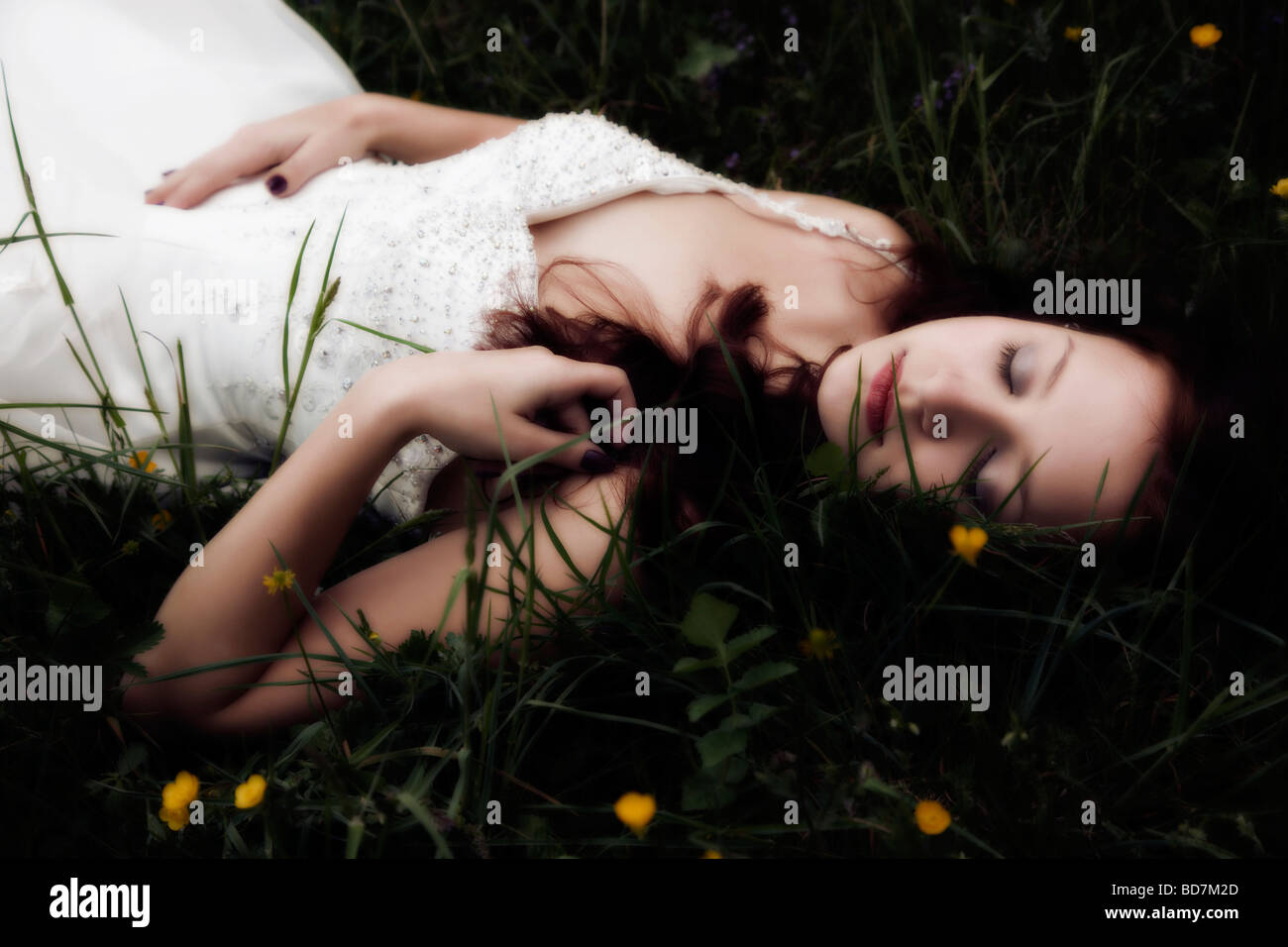 young woman in bridal dress lying in grass Stock Photo - Alamy