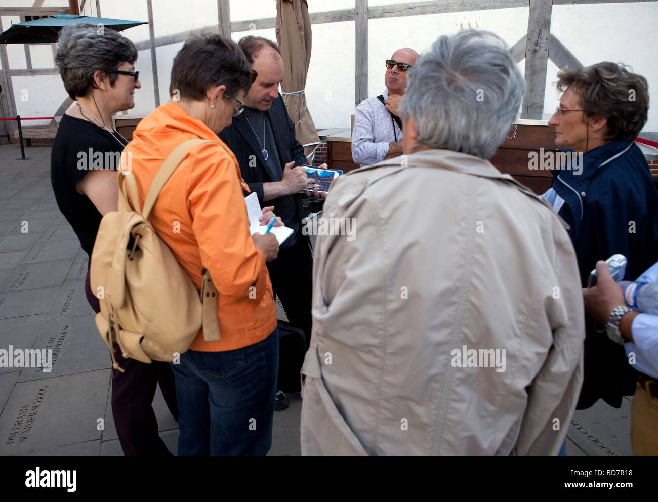 Tourists listening to tour guide outside of The Globe Theatre ...