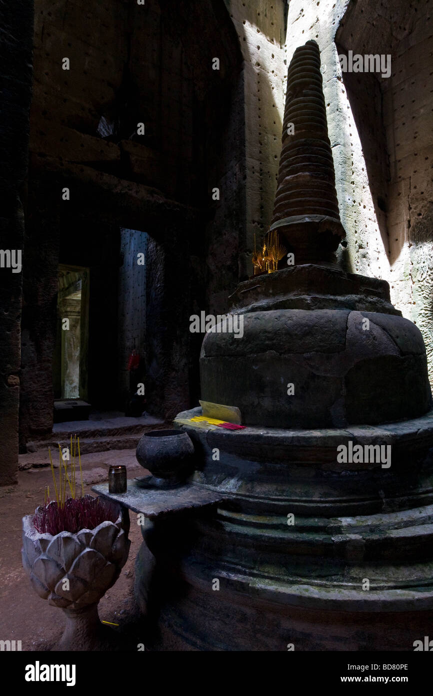 A stupa inside a standing building at Ta Prohm, with incense sticks ...