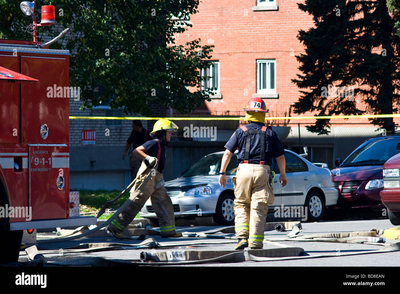 Firefighters rolling the hose. A firefighter woman among them Stock ...