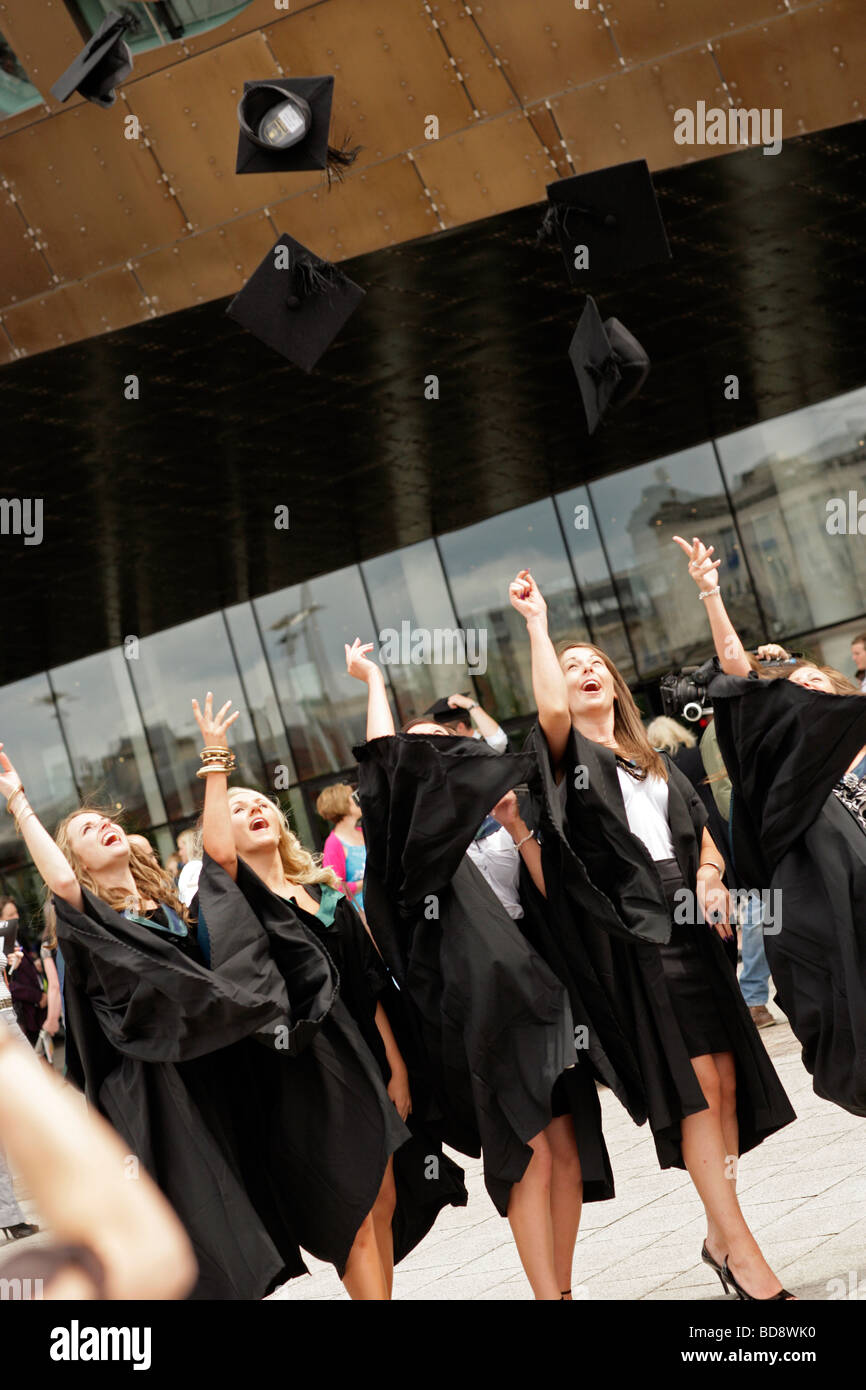 Young graduates on graduation day throwing mortar board hats in the air ...