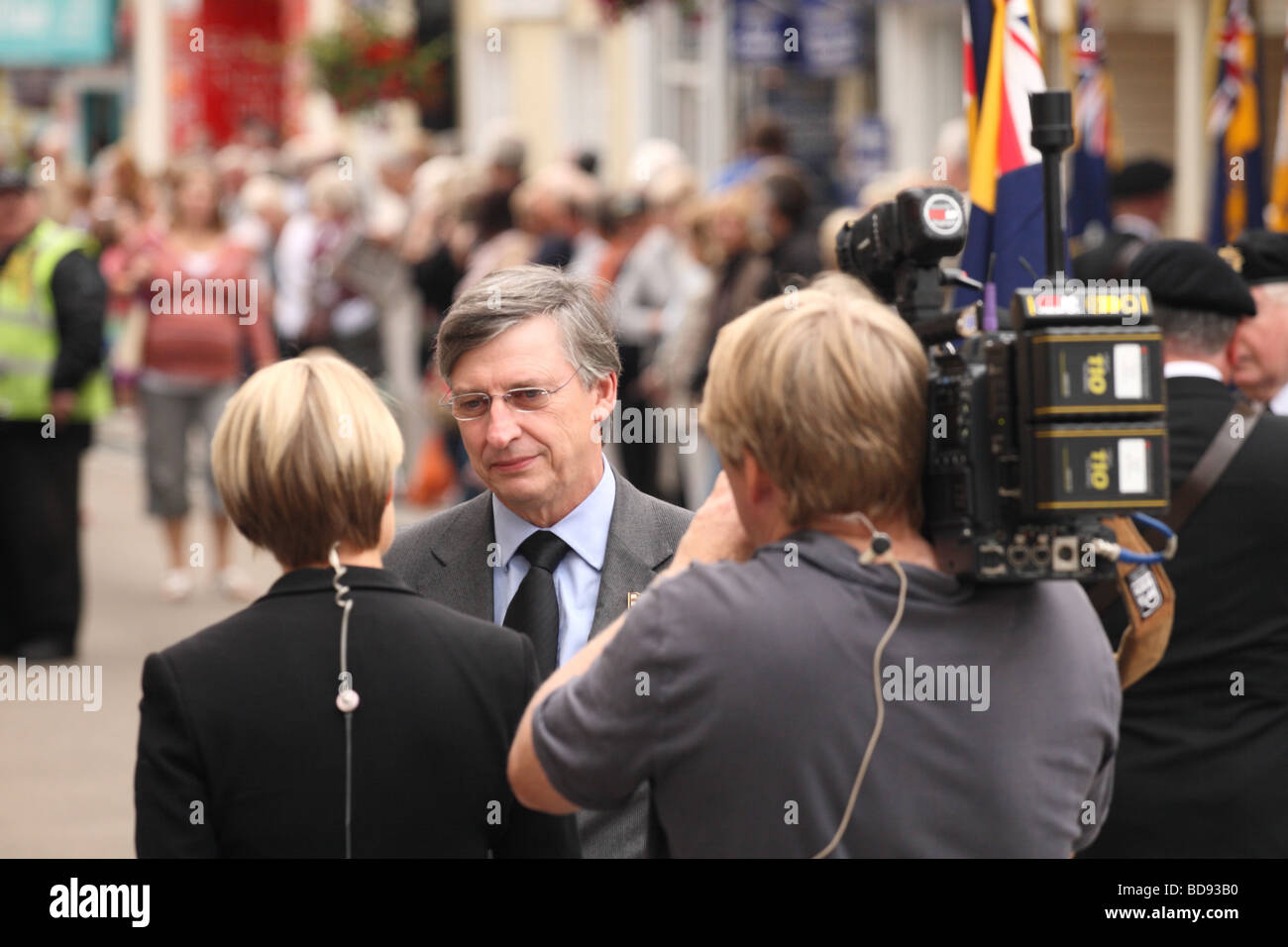 Television news film crew and TV presenter working at an outside ...